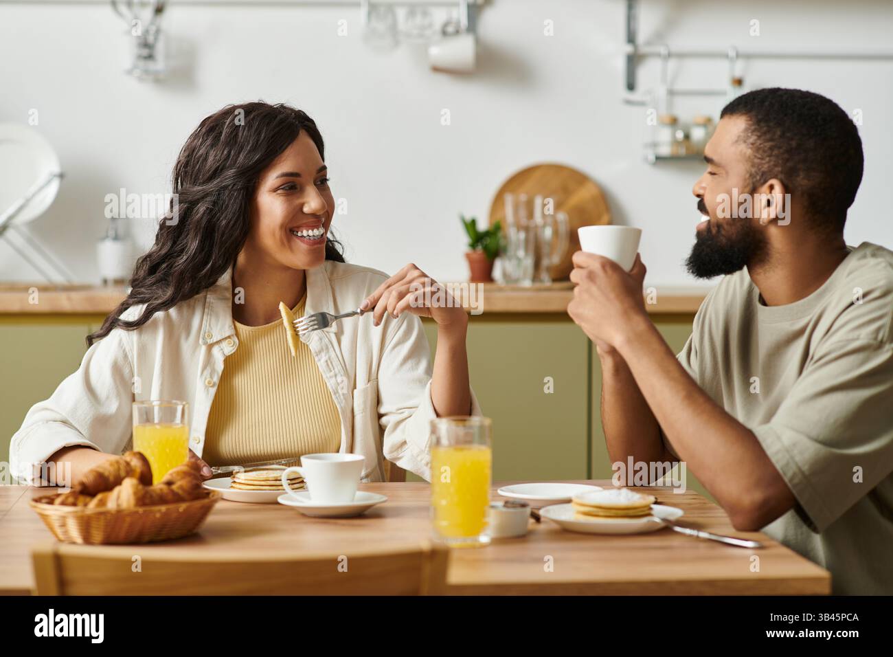 A couple enjoys a cozy breakfast at home, laughing and sharing sweet ...