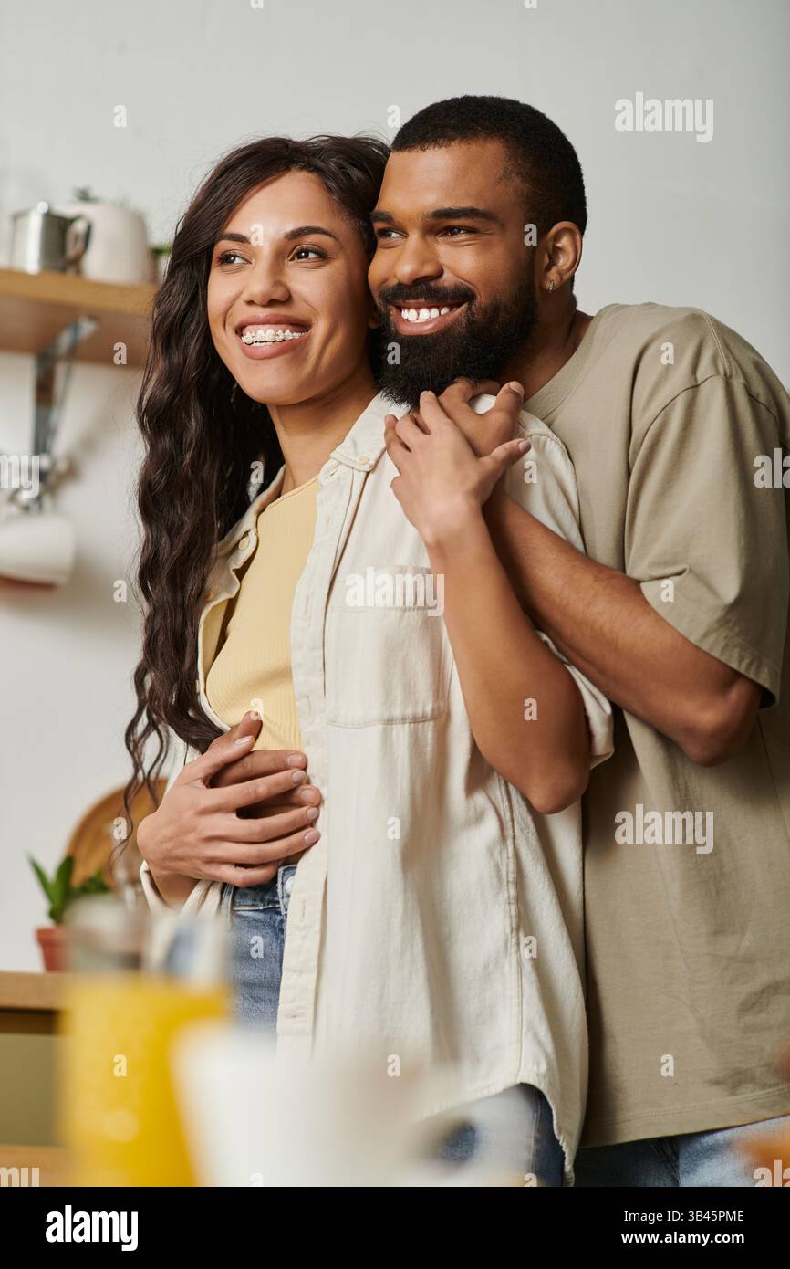 A loving couple shares a joyful moment at home, embracing each other ...
