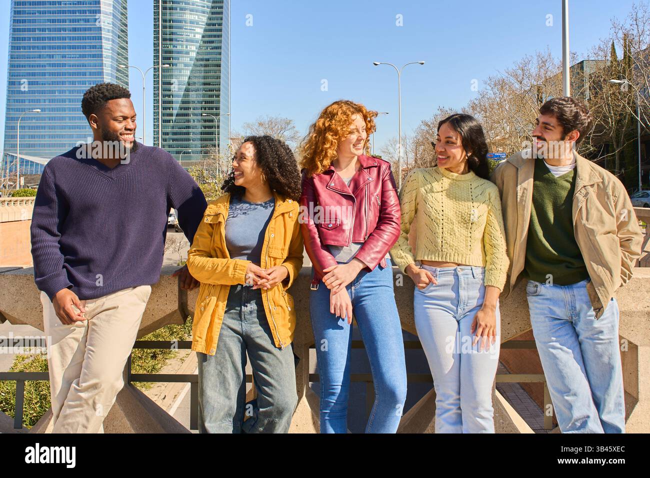Five young students enjoying a conversation on a bridge in the city ...