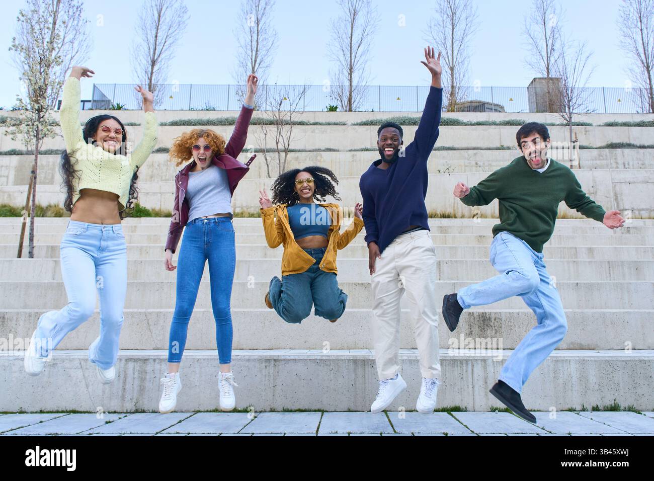 Five cheerful multi ethnic students jumping joyfully together on a ...