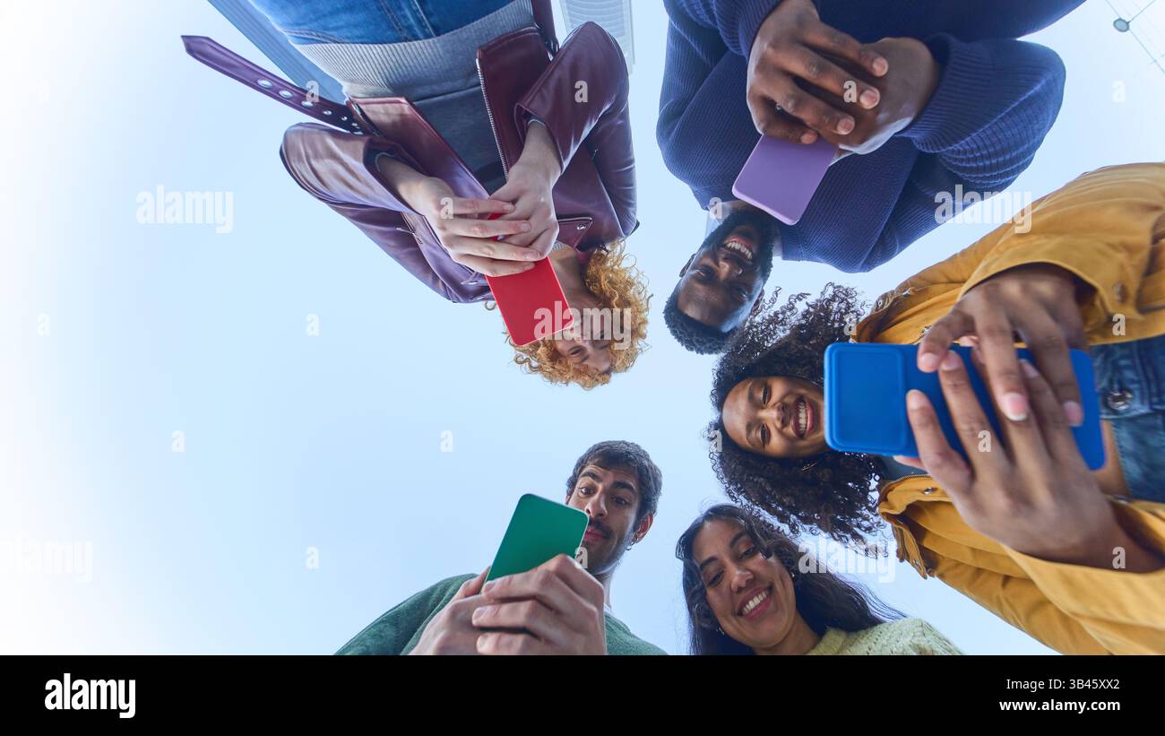 Happy students forming a circle outdoors, sharing content on their ...