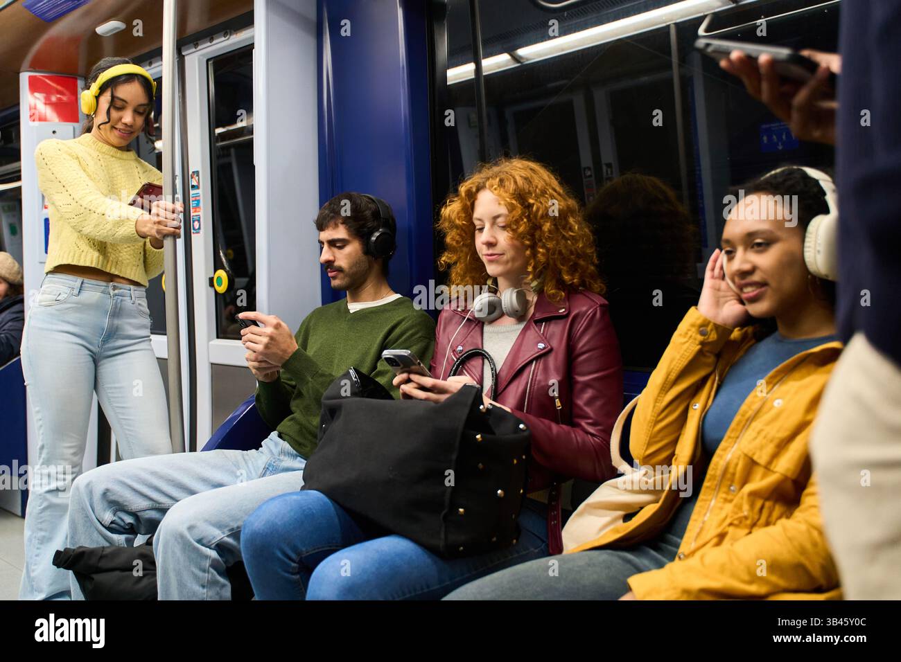 Passengers engaging with smartphones and wearing headphones while ...