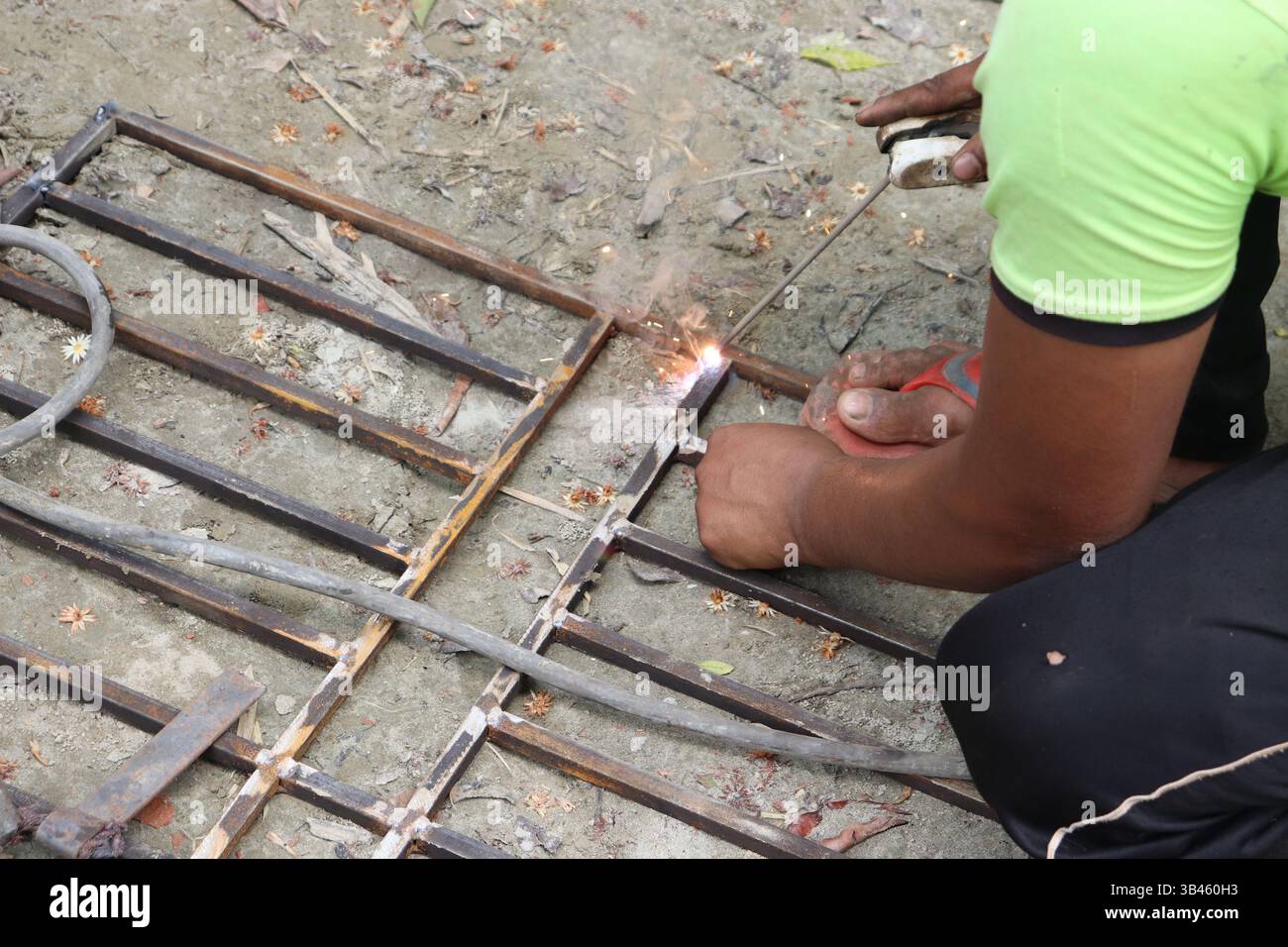 Close-up captures a dark-skinned welder using welding rods to fuse a ...