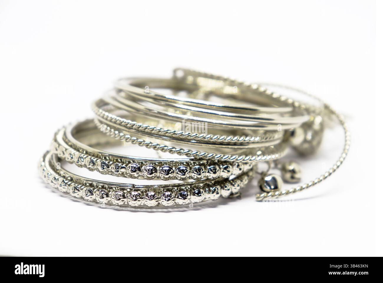Focus on a shiny stack of silver-toned bangles, some with attached tiny ...