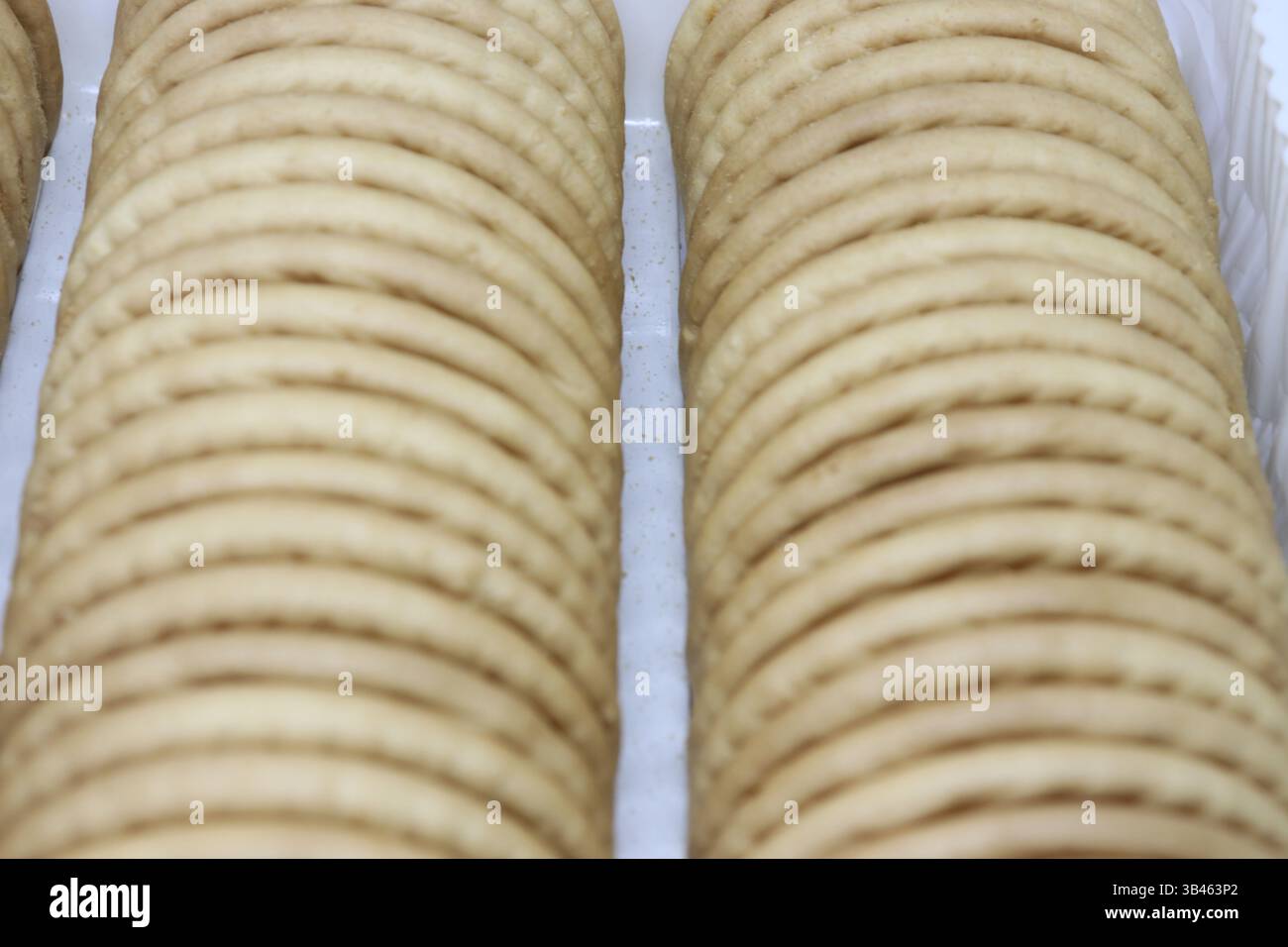 This close-up shot features neatly stacked rows of brown cookies in a ...