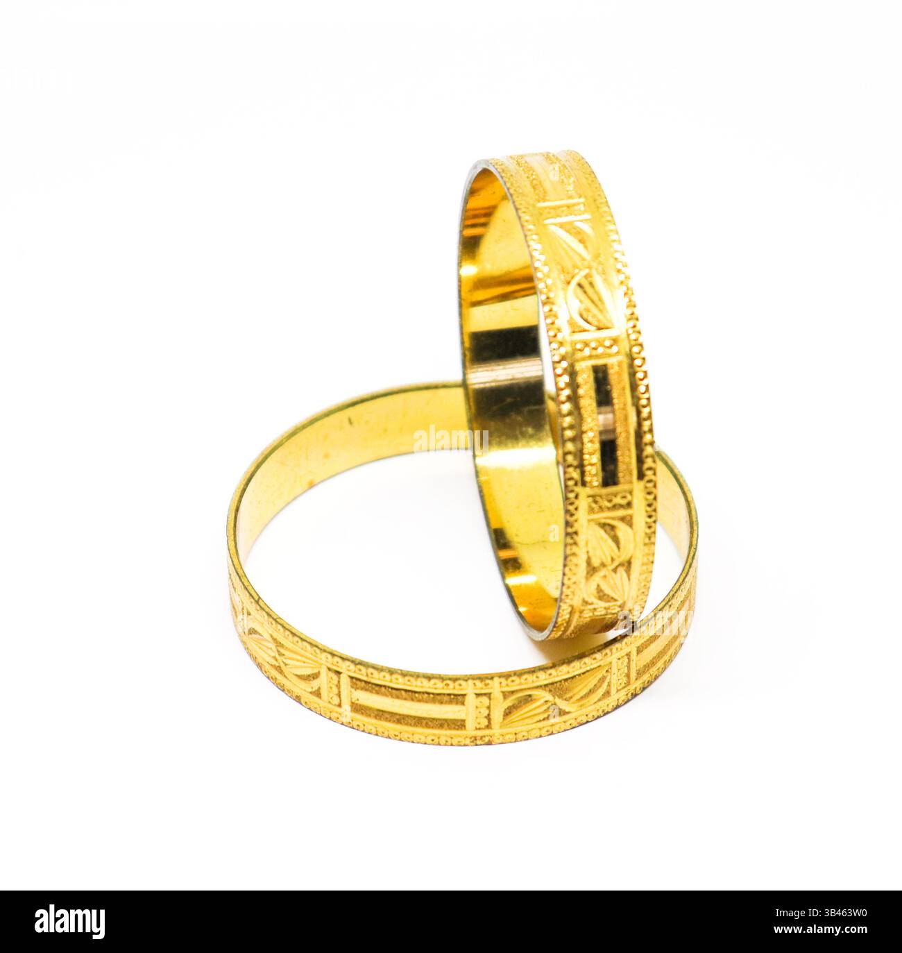 Shot shows two shiny golden bangles with intricate patterns stacked on ...
