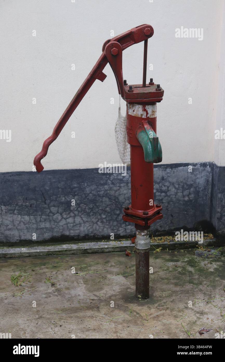 Captures the weathered texture and utility of a red iron manual water ...