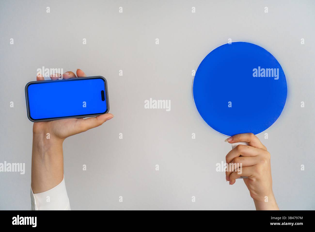 cell phone blank blue screen mockup and blue round sign. hands of ...