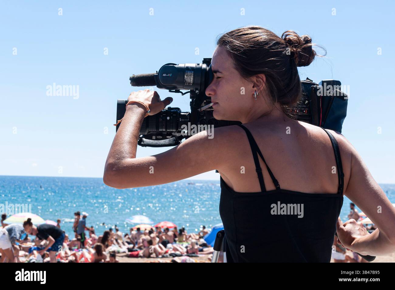 Young woman journalist working with a television camera on the beach ...