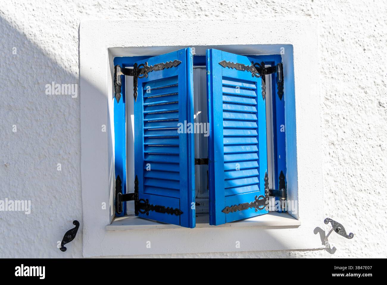 Traditional blue wooden window shutters on a white textured wall in ...
