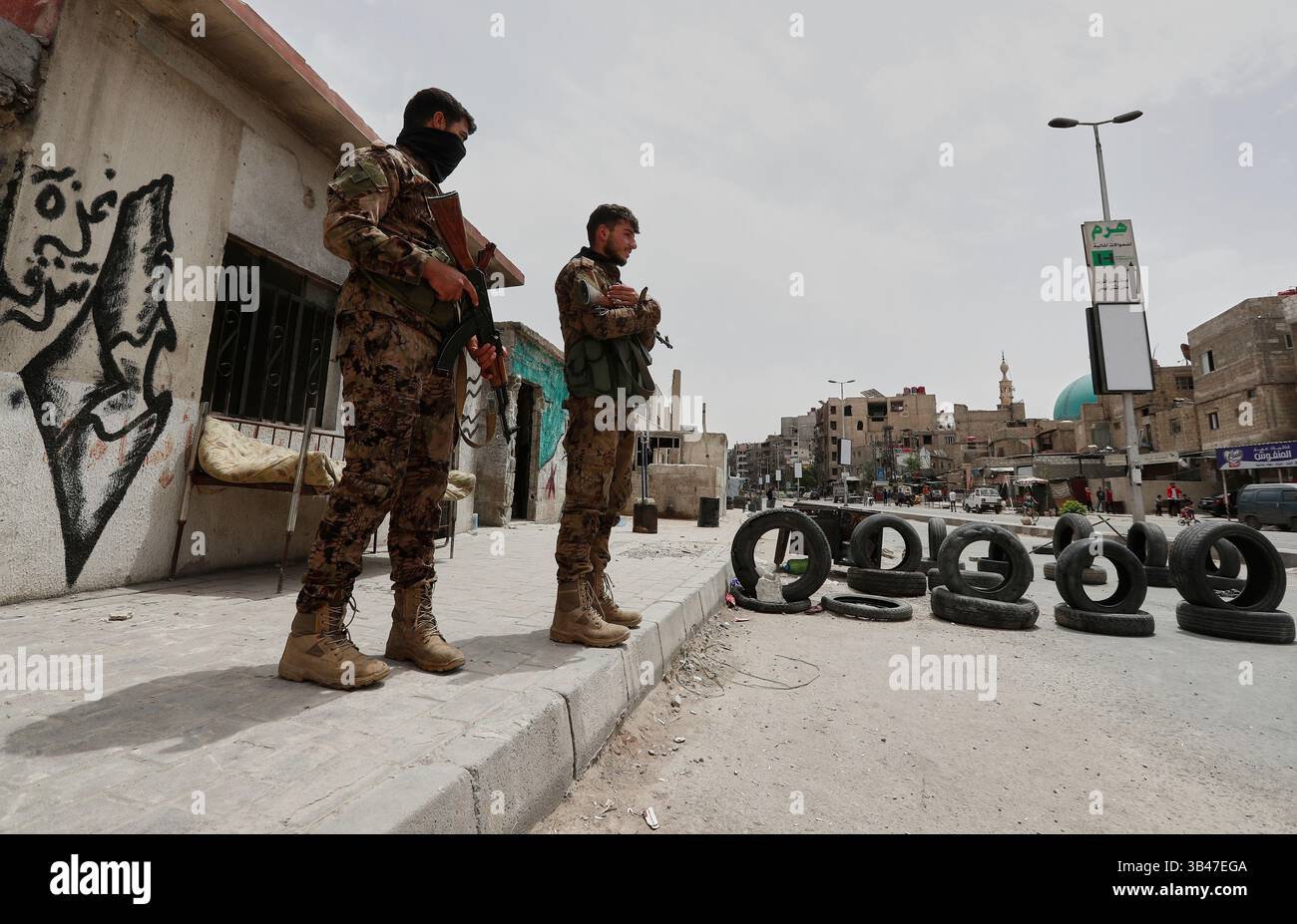 Syrian government security forces stand guard on their checkpointat one ...