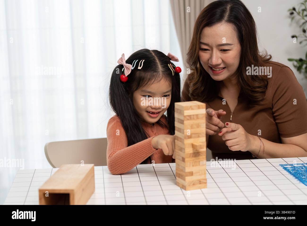 Back to School Fun and Learning. A mother and daughter enjoying a game of Jenga, fostering ...