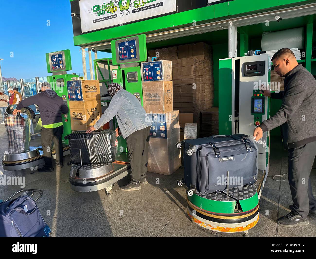 Worker wrapping suitcase with transparent protection film atairport ...