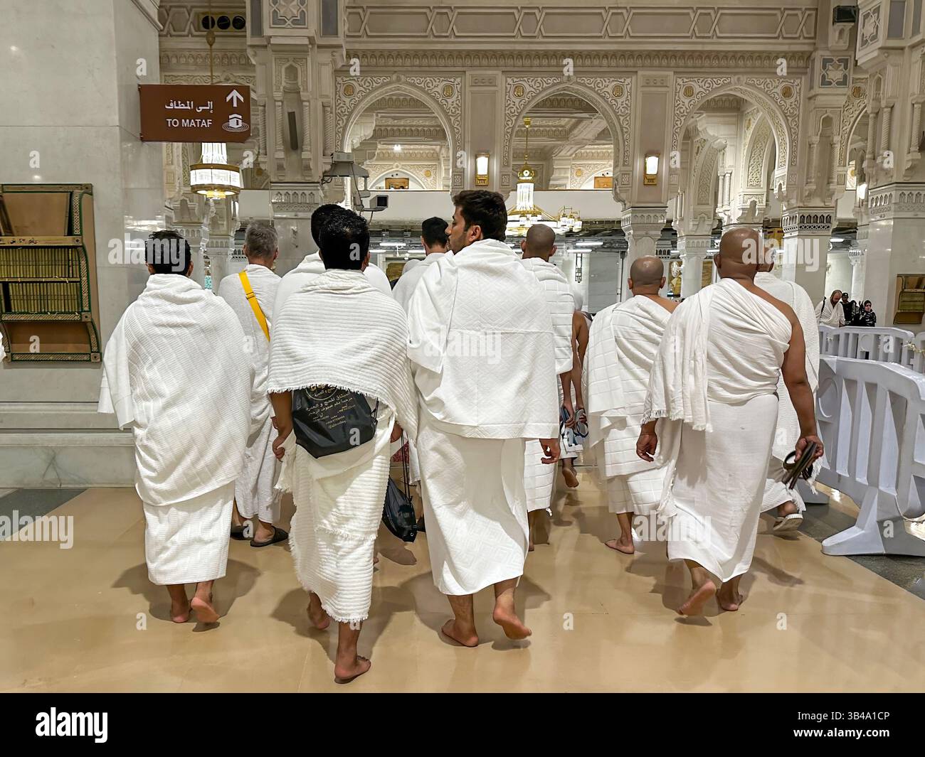 Male pilgrims in ihram go to pray in Al Haram Mosque. Rear view. Saudi ...