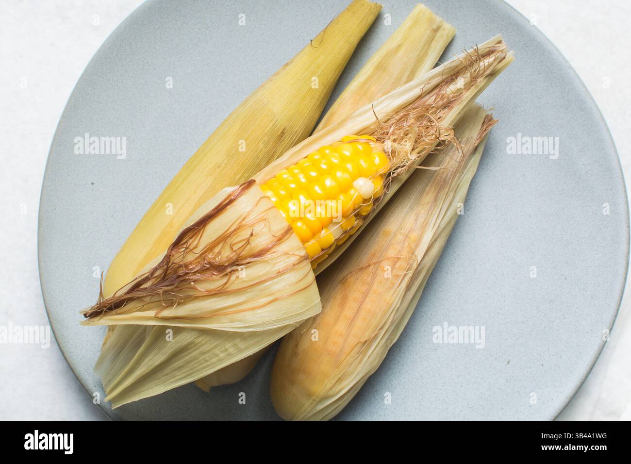 Overhead view of boiled cob of corn on a grey plate, top view of whole ...