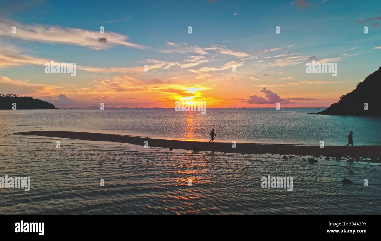 Two tourists are walking on the scenic sandbar connecting Koh Ma to Koh ...