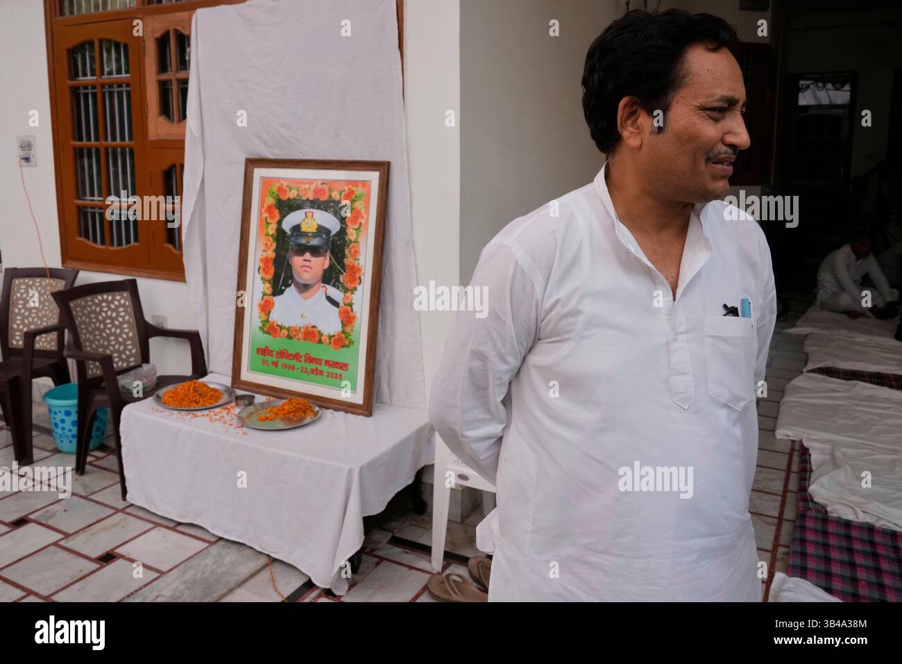 Sunil Swami stands next to a framed portrait of his son-in-law and ...