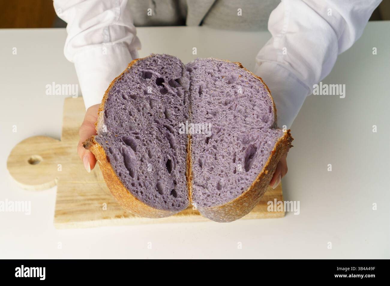 Purple Unusual and creative colored artisan sourdough bread in a cross section in the hands of a ...