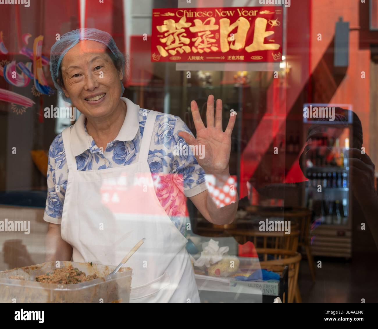 View of a female restaurant worker smiling and waving her hand through ...
