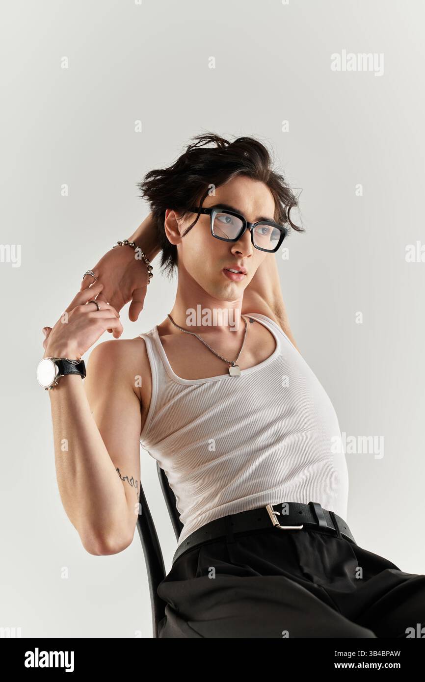 A slim young man in a white tank top poses confidently in a ...