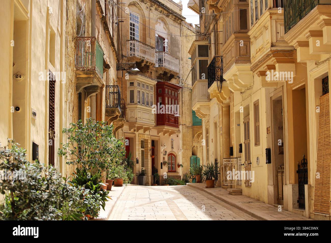 Traditional Maltese street with colorful balconies and potted plants in ...