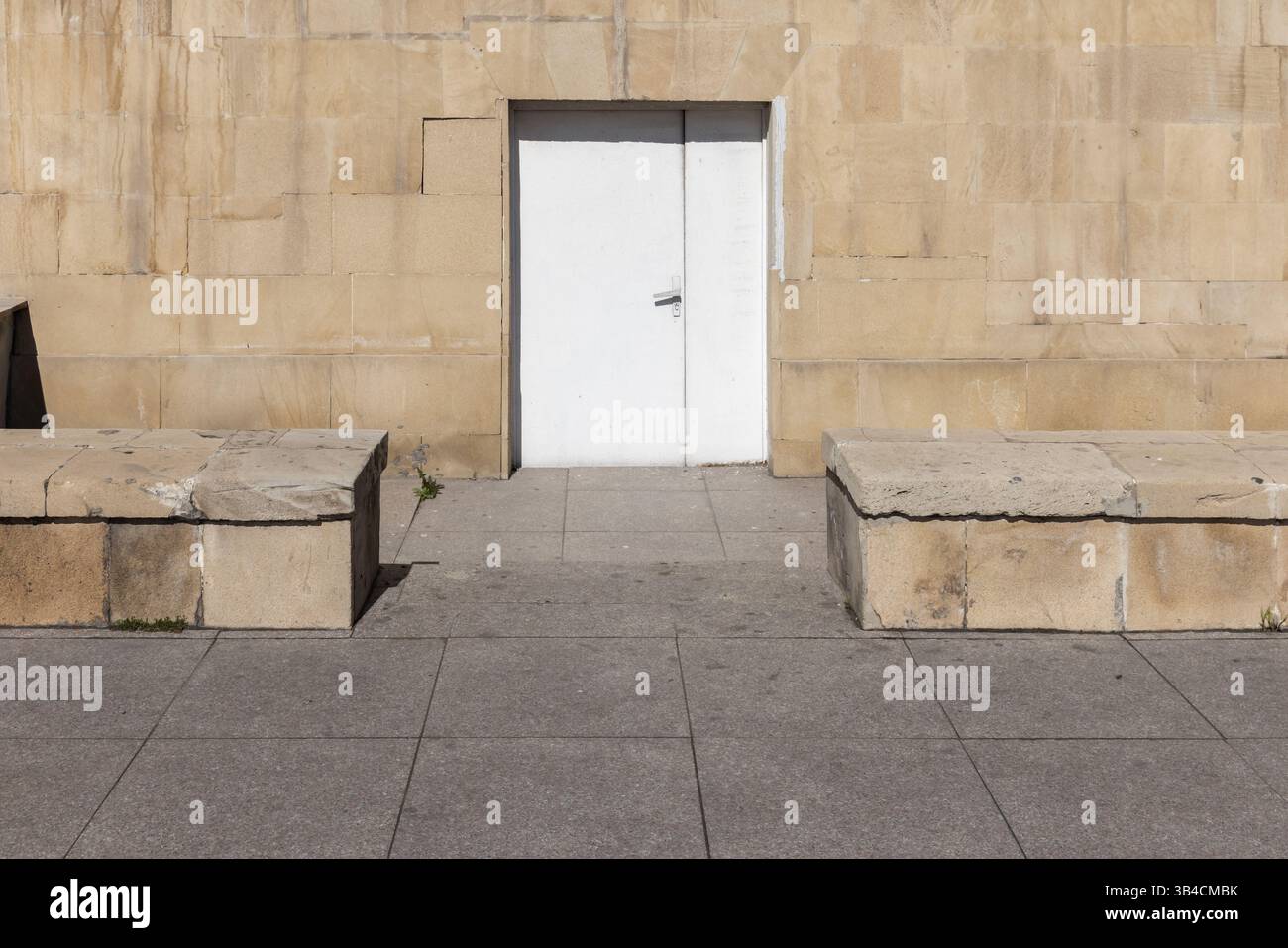 A simple white door set into a textured stone wall with surrounding ...