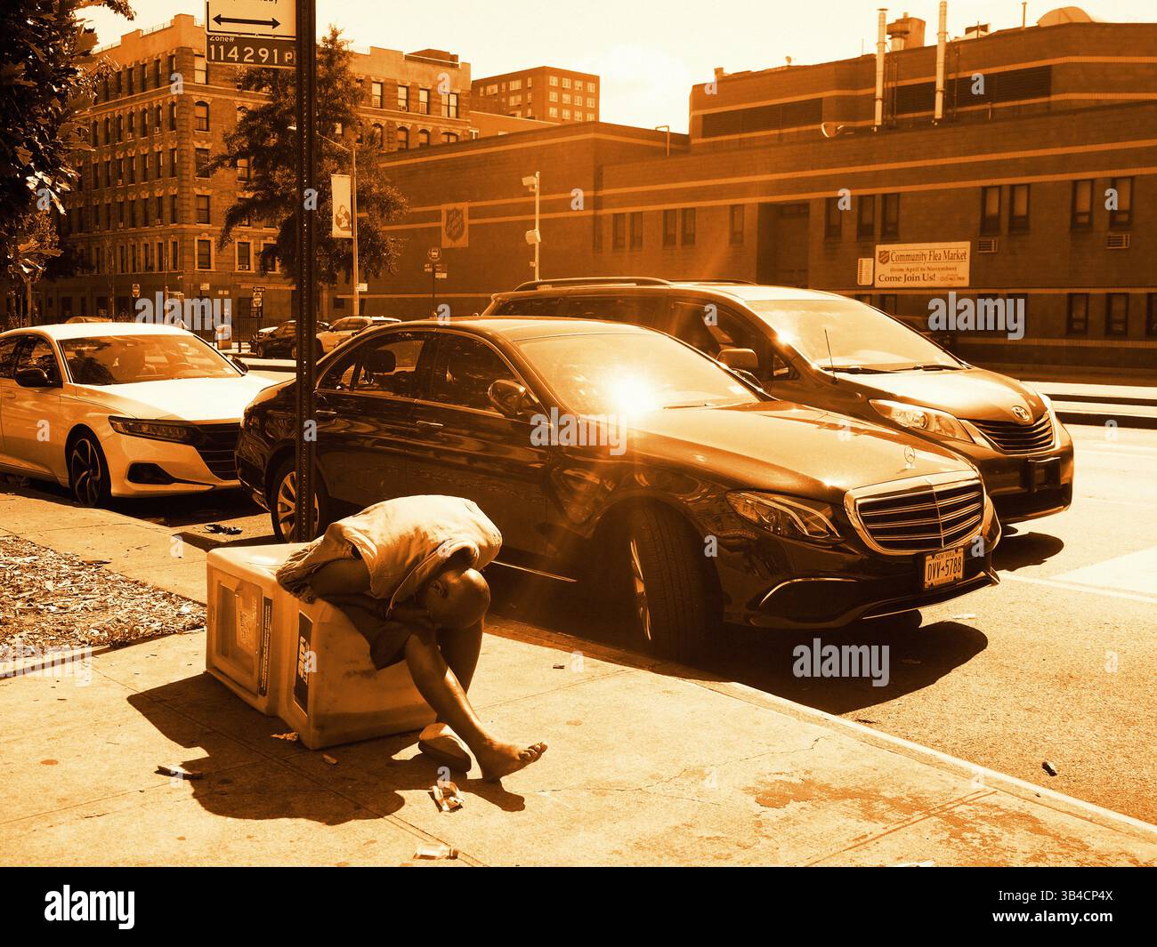 Homeless man sleeping on sidewalk beside luxury cars in Harlem under ...