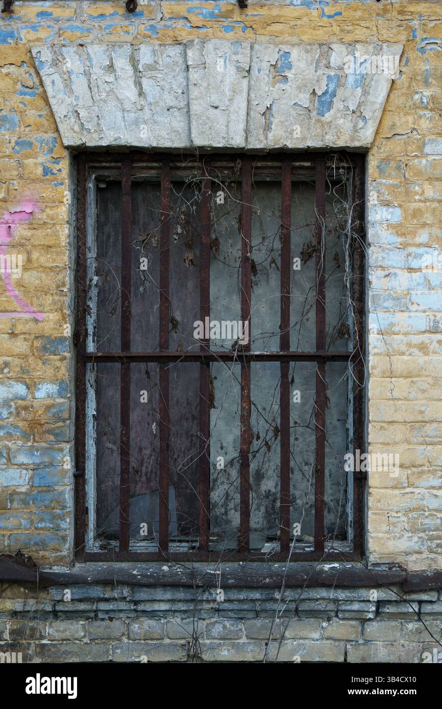 A haunting image of an old barred window set into a weathered brick ...