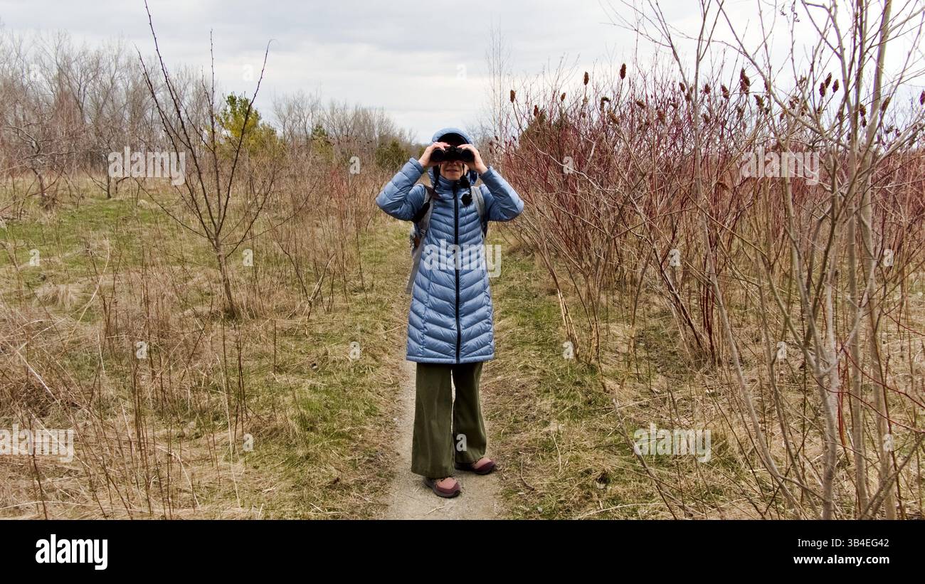Captured mid-observation, a female birdwatcher participates in an eco ...