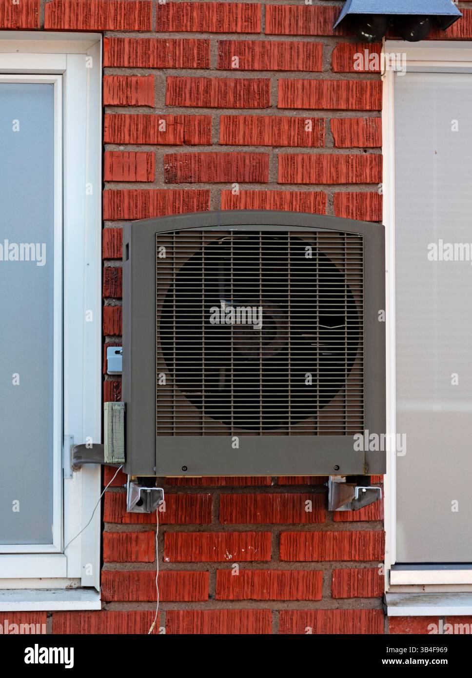 Red brick building facade featuring a mounted ventilation fan and white ...