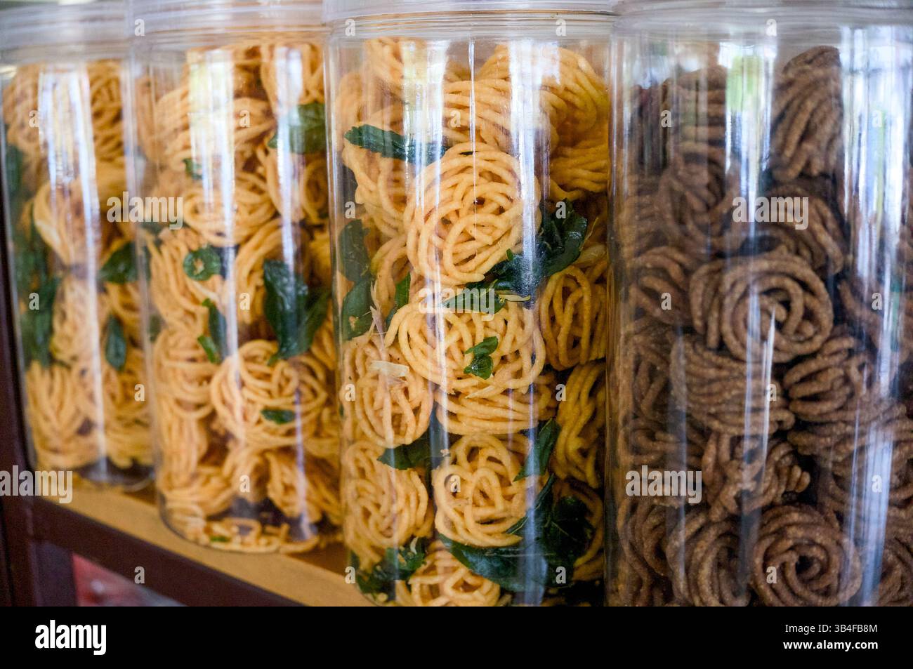 Various types of crispy snacks displayed in transparent jars at a ...