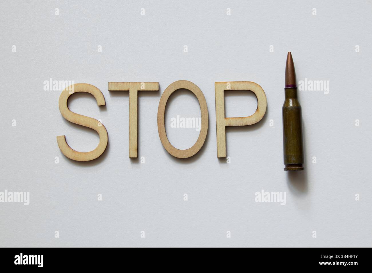 The word stop laid out in wooden letters, with a bullet on a white ...