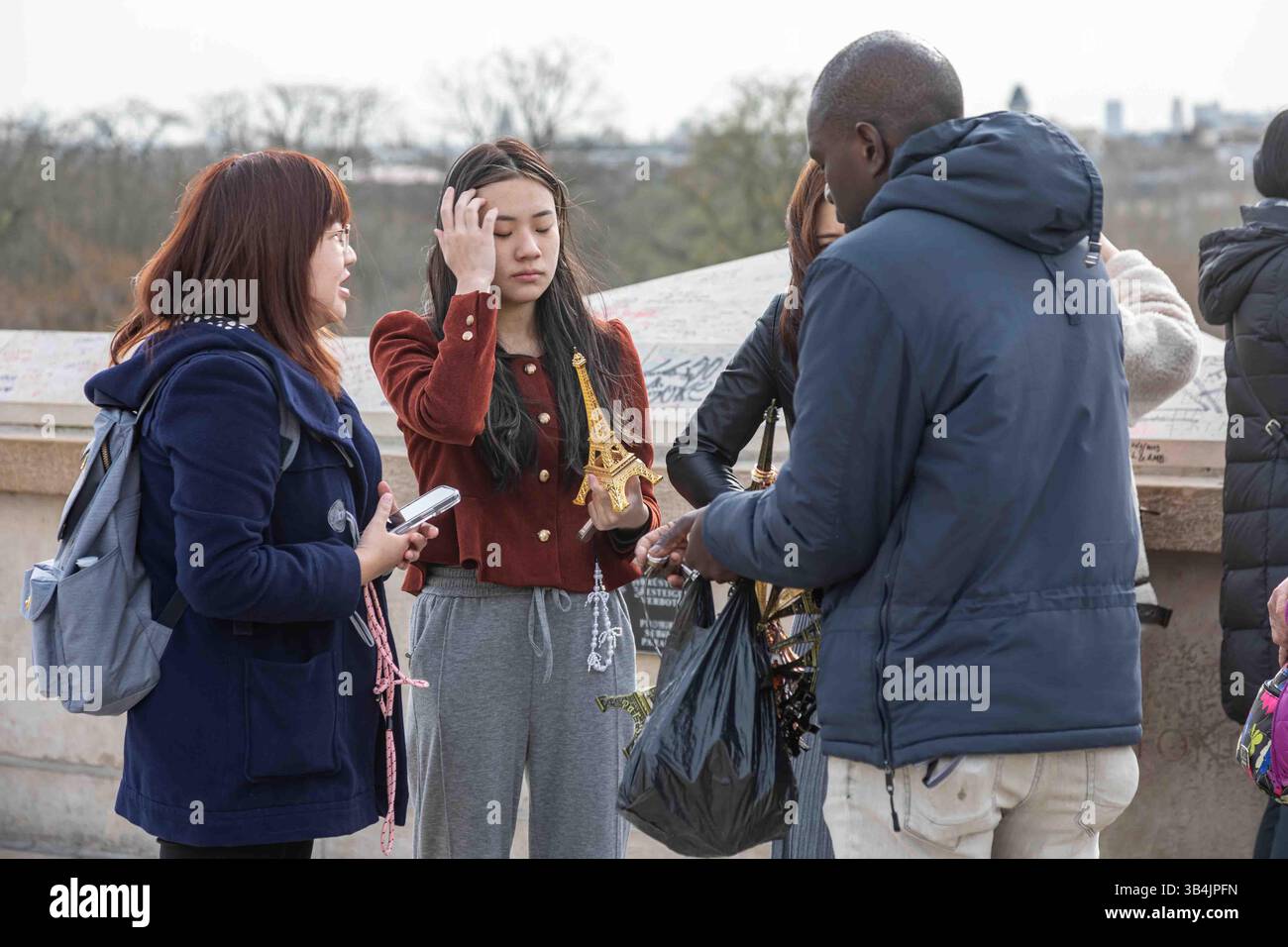 Street vendor selling souvenir miniature Eiffel Tower to tourists on ...