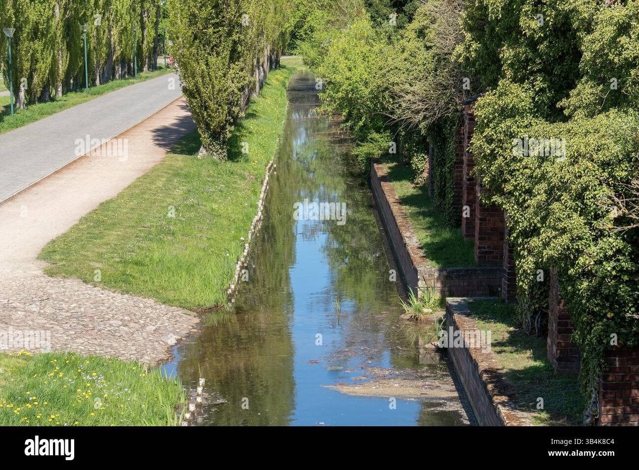 A deep moat at the foot of the massive stone walls of an ancient castle ...