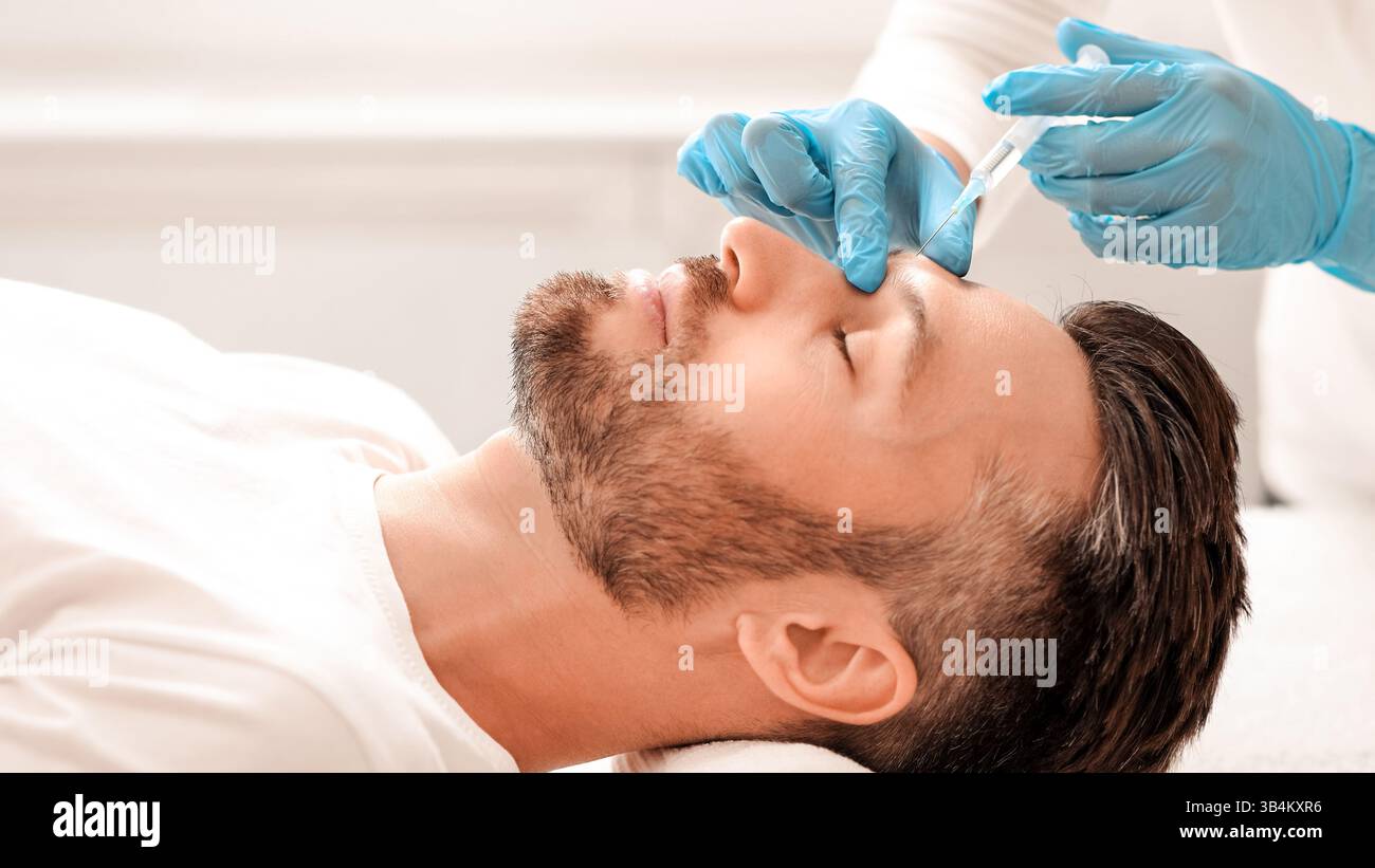 Side view of bearded man getting beauty injection in salon Stock Photo ...