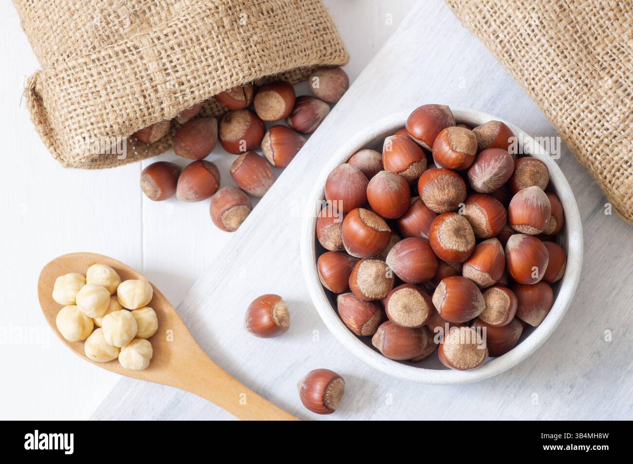 Hazelnut, whole and peeled hazelnuts in bowl and wooden spoon on white ...