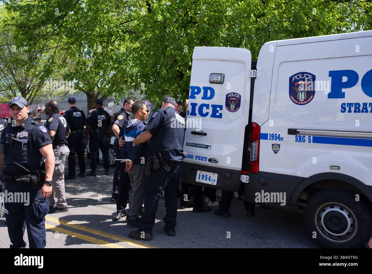 A man in civilian clothing is being arrested by two NYPD officers in ...