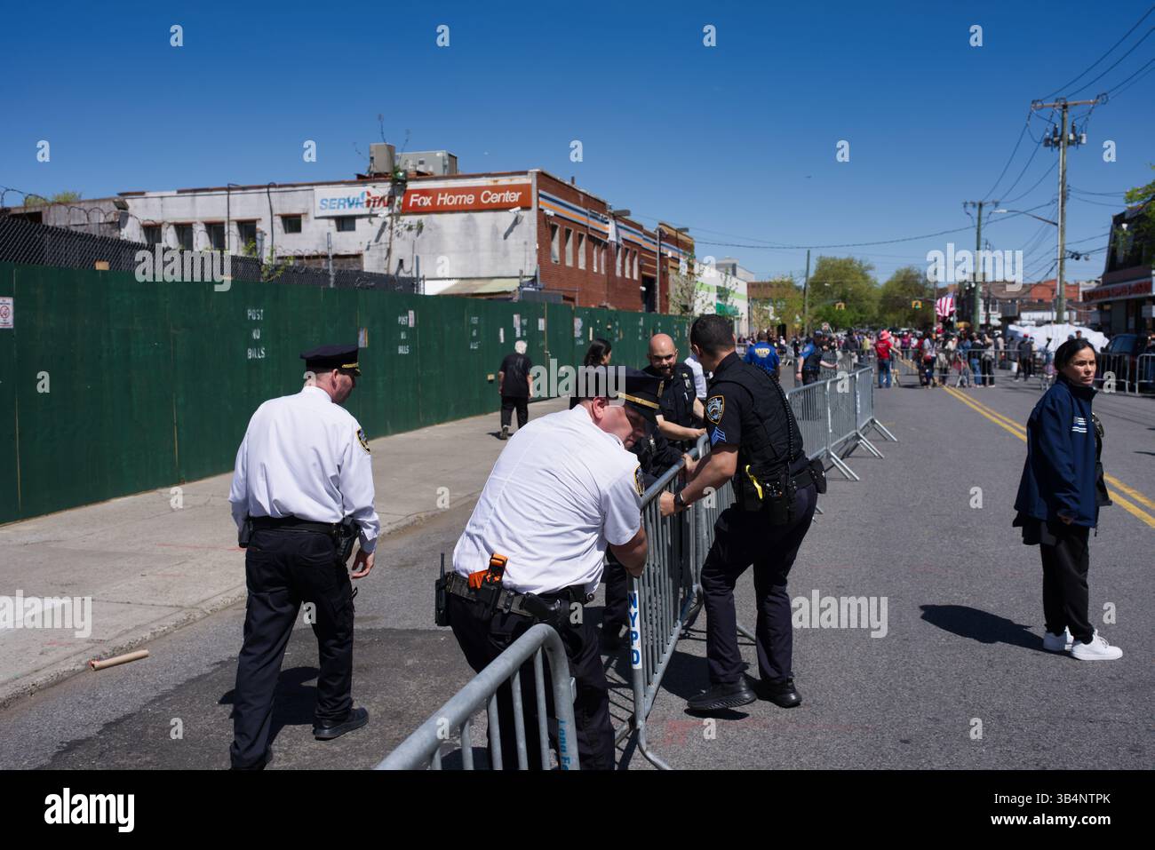 Multiple NYPD officers in uniform stand behind a metal barricade on a ...