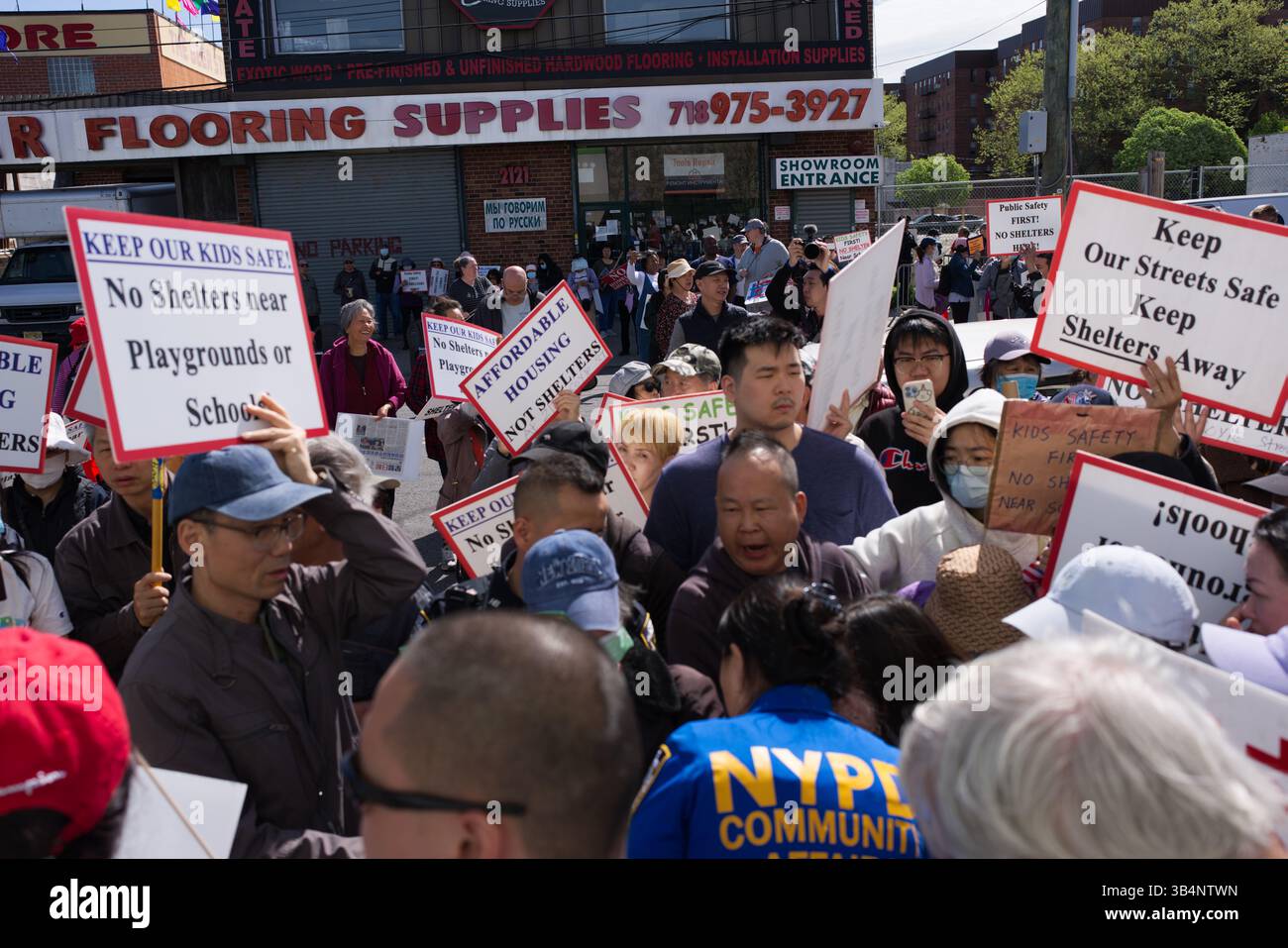 A daytime outdoor photo shows a large group of protestors holding signs ...