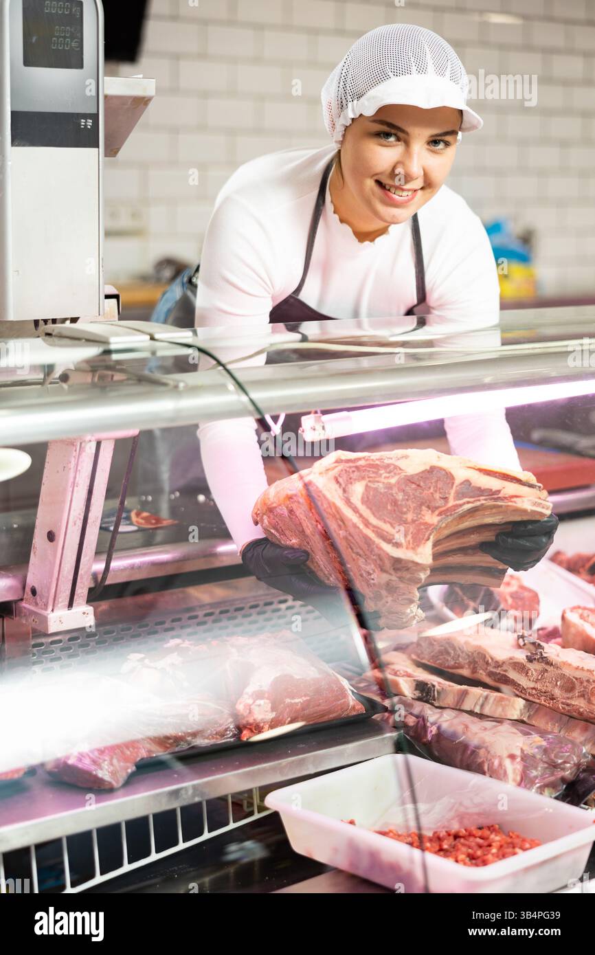 Female butcher demonstrating fresh raw veal chop on ribs Stock Photo ...