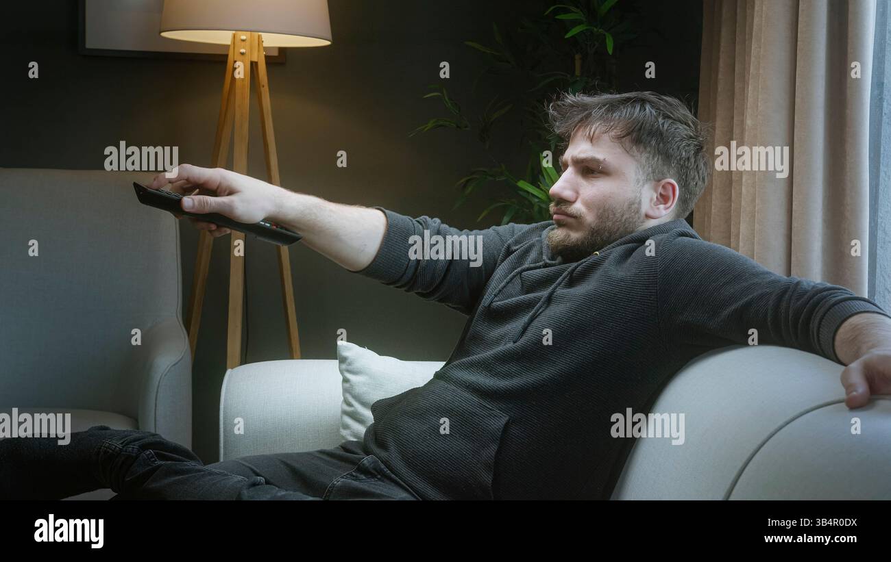 Man Sitting on Couch Watching TV with Remote Control in Hand Stock ...