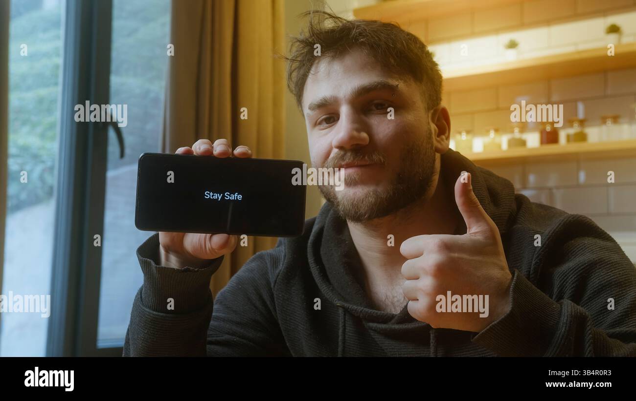 Man Showing Smartphone With Stay Safe Message and Giving Thumbs Up at ...