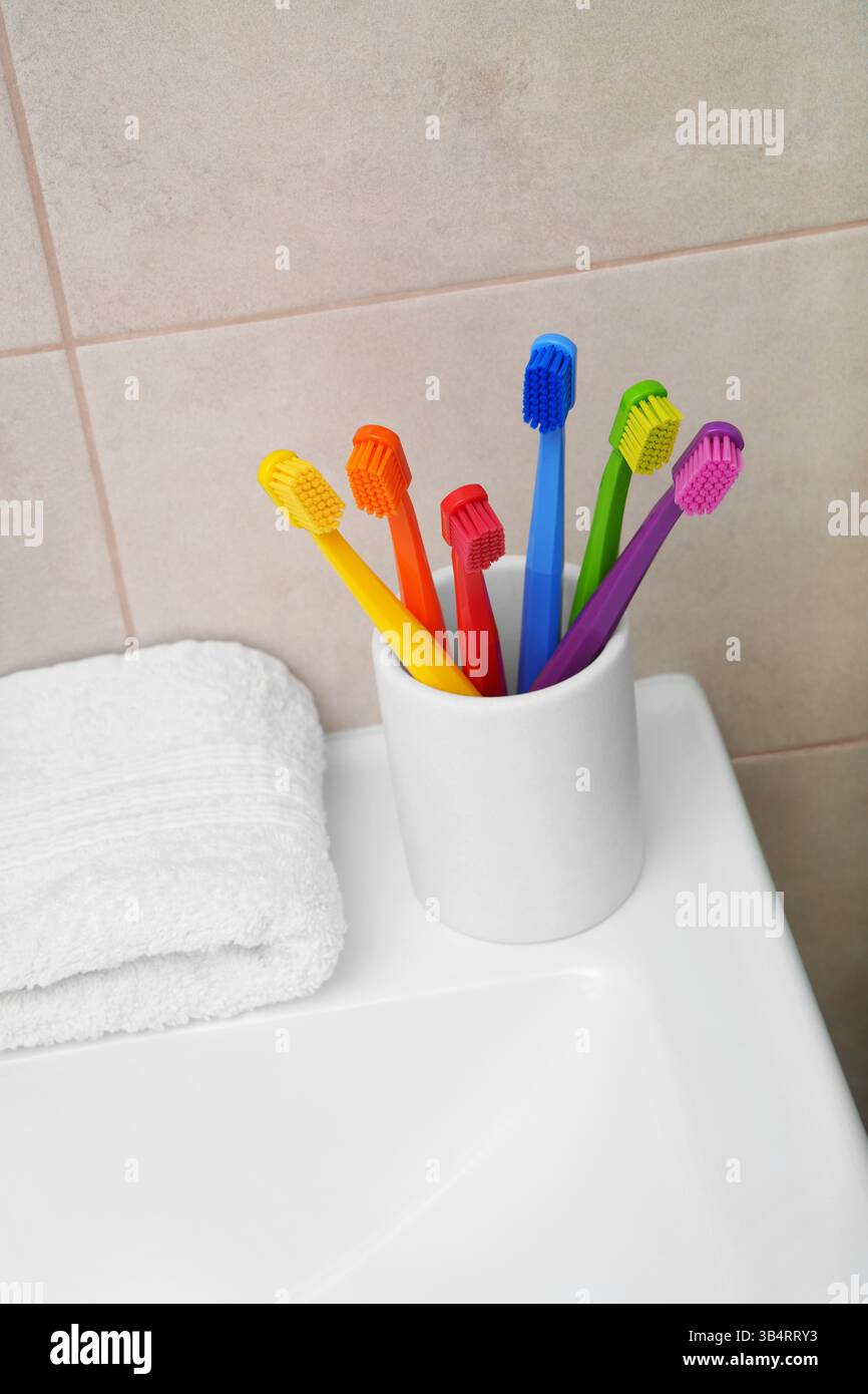 Multicolored toothbrushes. Six bright toothbrushes in a white glass in ...