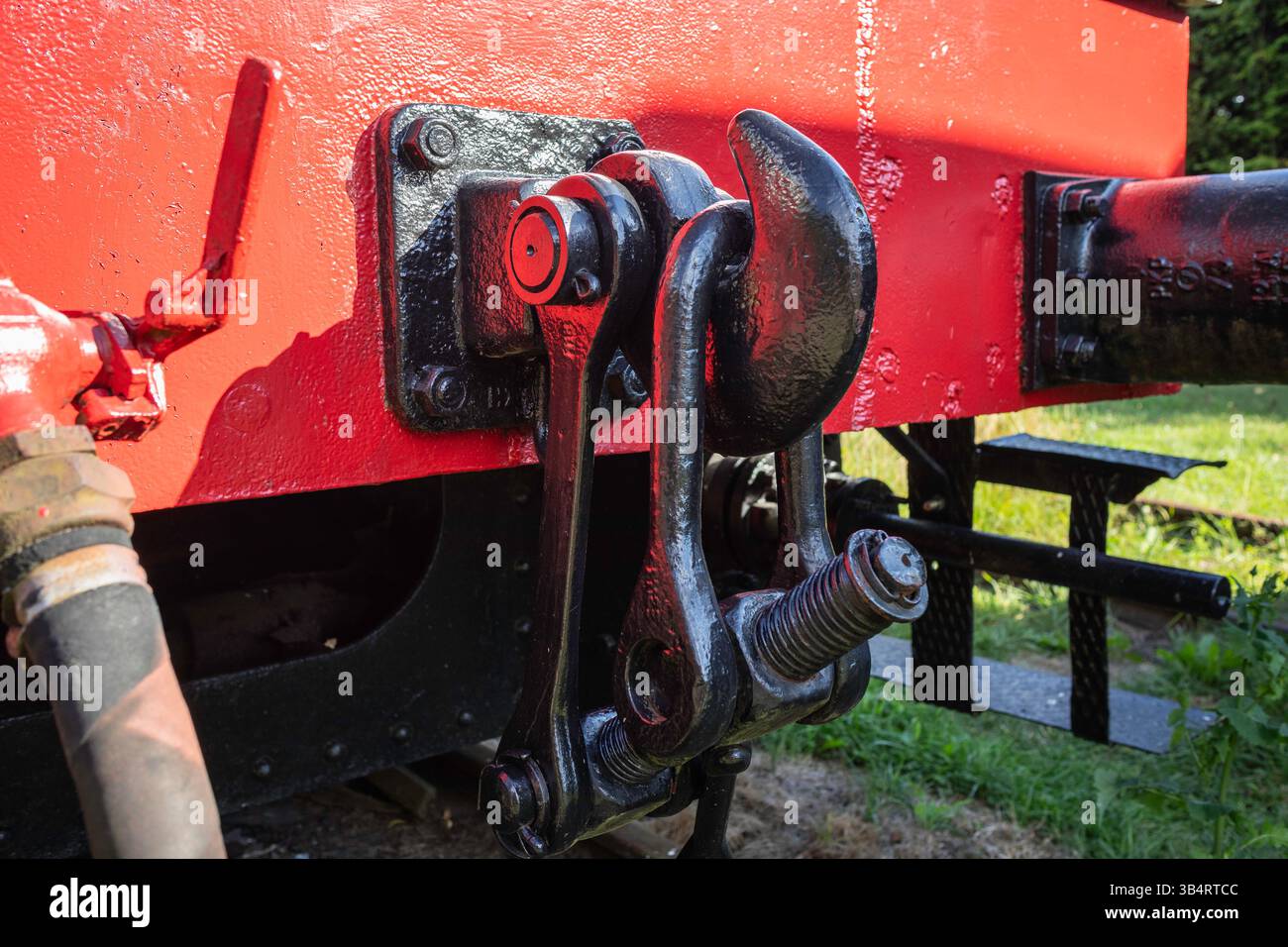 A red train with a black and white chain. The chain is attached to the ...