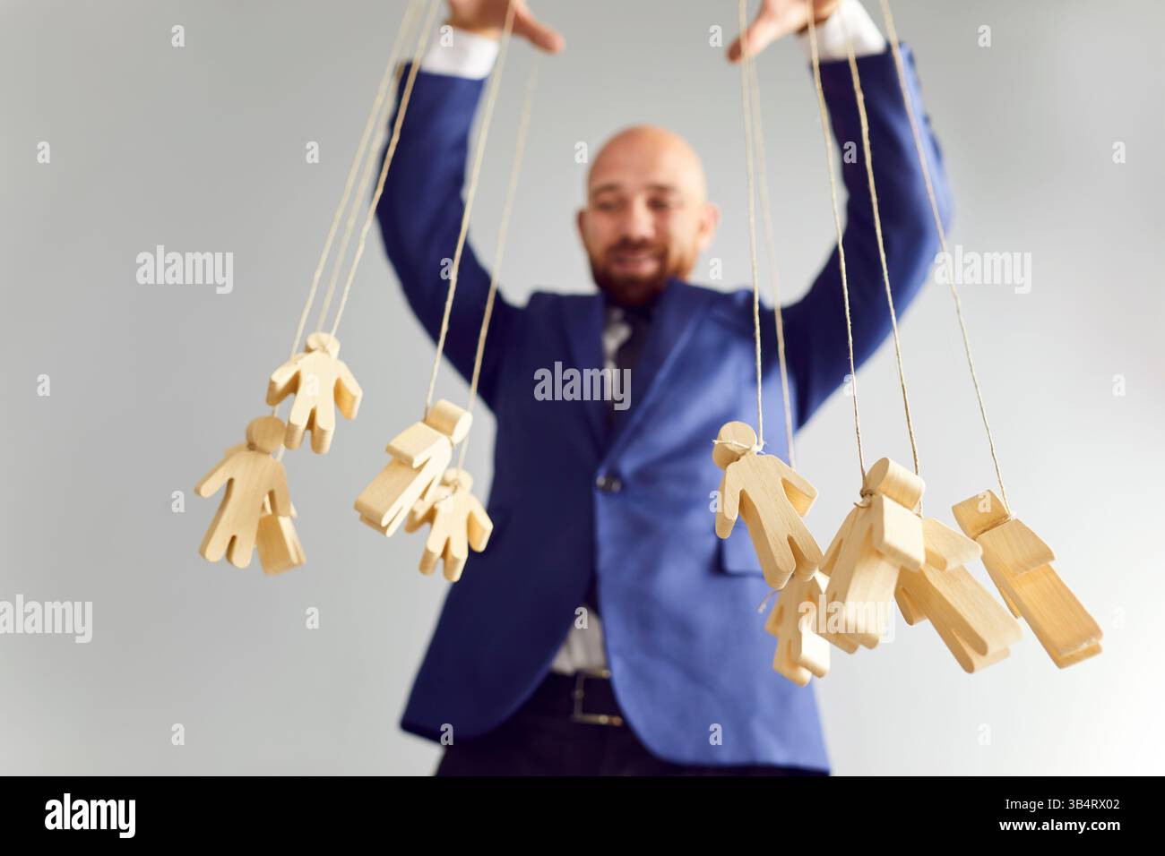 Business puppet master playing with human figures illustrating concept ...