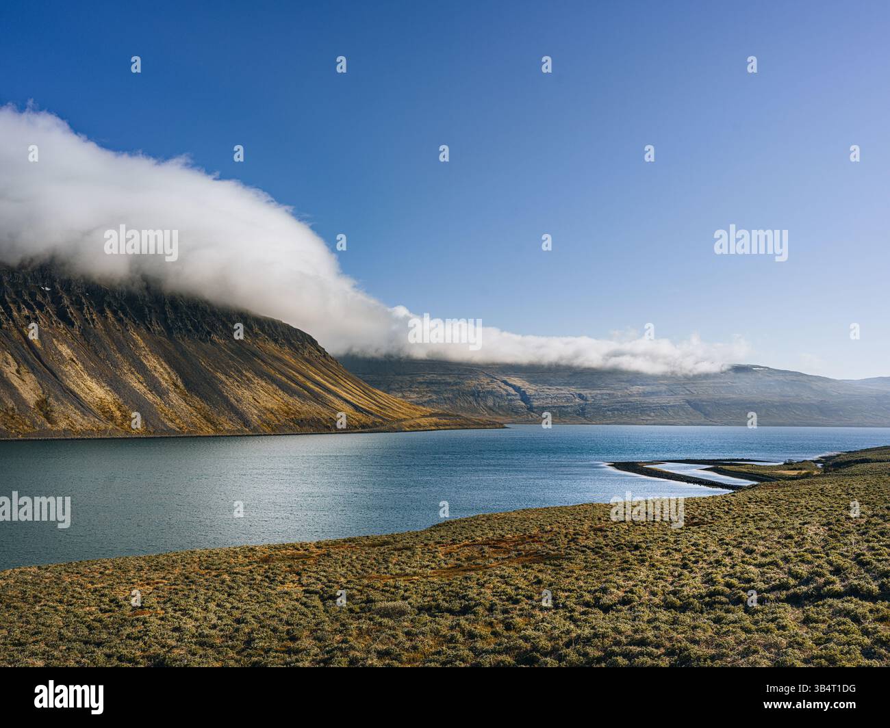 Low clouds hugging mountain slopes above an Icelandic fjord in the ...