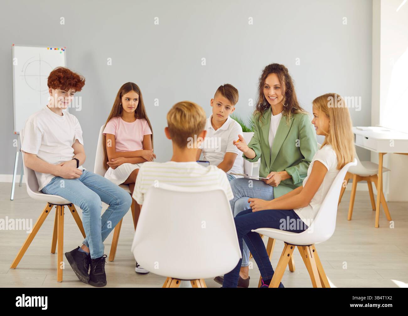 School psychologist woman having conversation with group of children ...