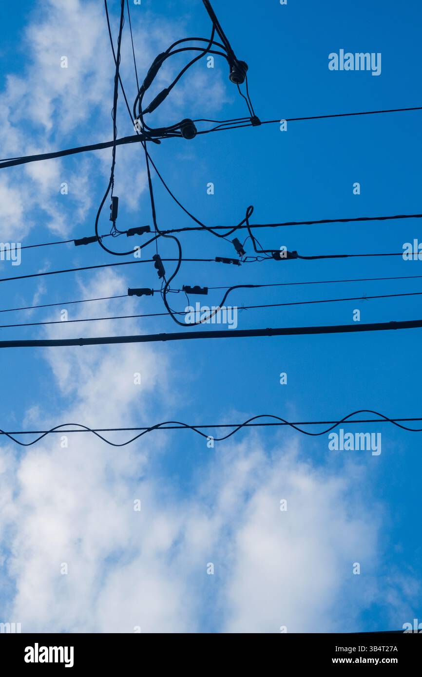 Tangled Power Lines Against a Bright Blue Sky and Scattered White ...