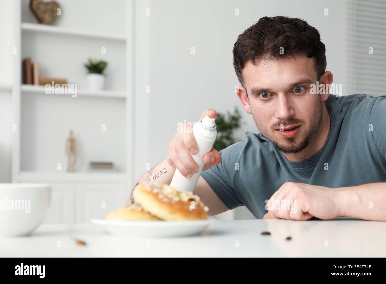 Emotional young man spraying insecticide onto pretzel with cockroaches ...