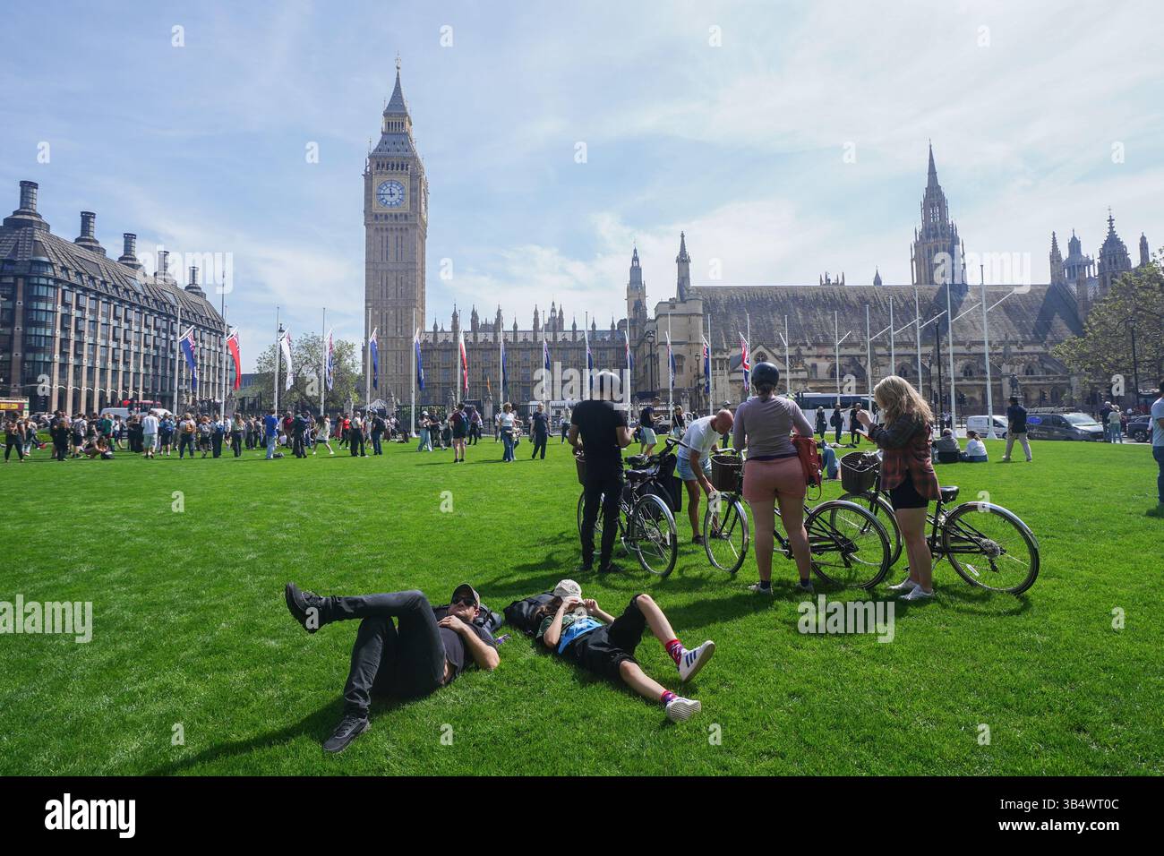 London UK 1 May 2025. Tourists relaxing in the sunshine in Parliament ...